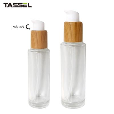 China botella de vidrio de la ronda de 30ml 50ml con el tipo de madera de la cerradura de la bomba del tratamiento del efecto en venta