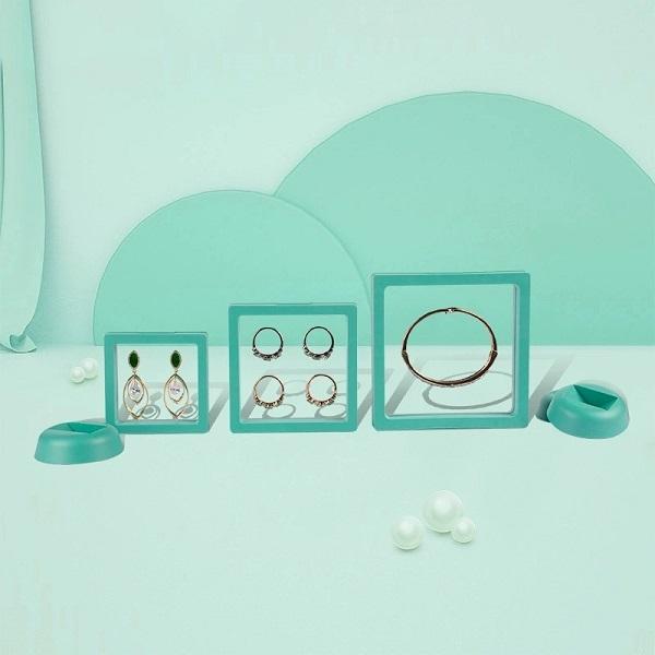 Mint green 3D floating film display frames with matching stands holding rings and earrings