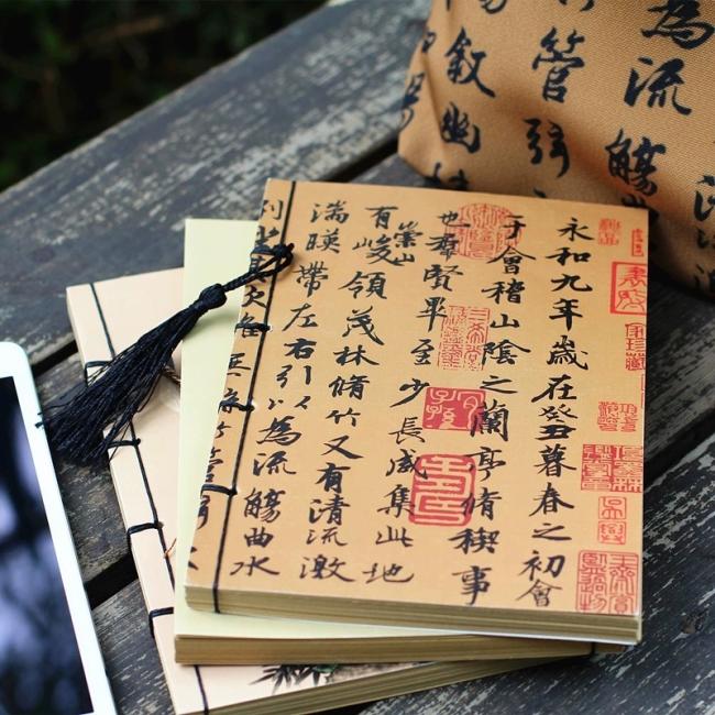 Thread-bound journal with decorative tassel displayed on rustic wooden surface