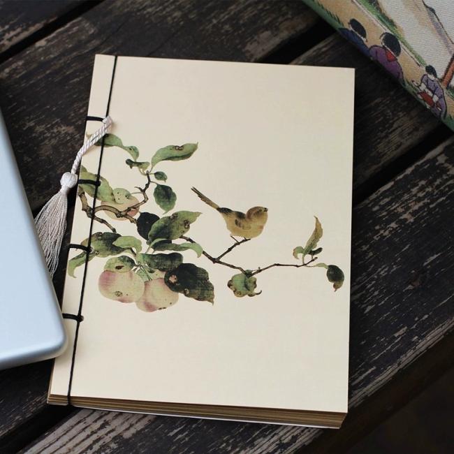 Front view of thread-bound journal featuring traditional bird and branch painting cover design