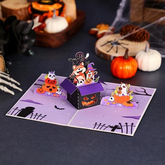 Close-up of open Halloween 3D pop-up greeting card showing laser-cut jack-o'-lantern box and cartoon dogs