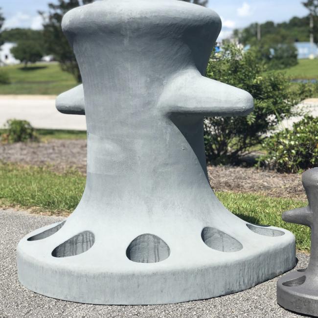 Mooring bollard installed at a commercial cargo berth showing the load-bearing body and mounting interface