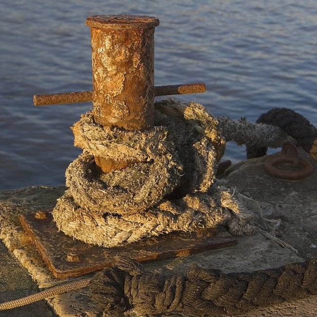 Close-up view of a marine mooring bollard with surface protection coating at a quay edge