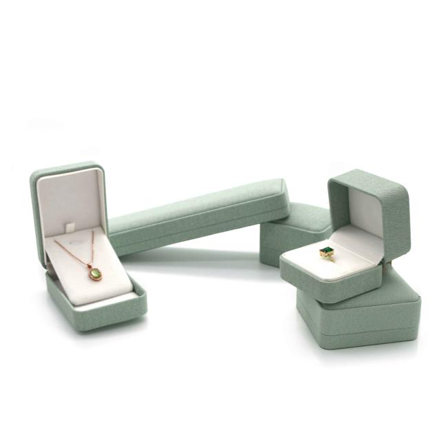 Elegant mint green linen jewelry box showcasing custom logo and interior compartments for rings, necklaces, and bracelets