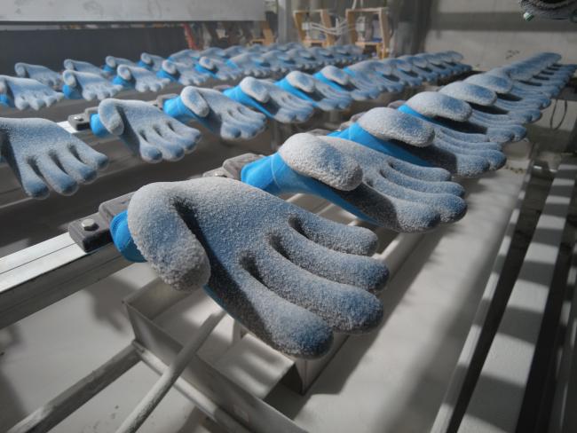 Close-up view of glove dipping process and machinery components