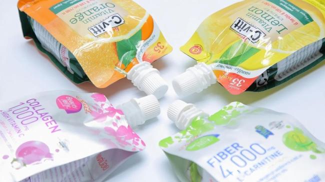 Flat lay overhead shot of 4 types colorful glossy spout pouches for vitamin fruit juice, collagen jelly and fiber drink, close view of white leak-proof plastic spout cap structure, food safe composite liquid packaging film for portable health beverage.