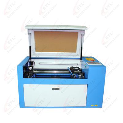 Cina La mini tagliatrice del laser di CNC con su rotatorio/giù del dispositivo presenta per il materiale del metalloide in vendita