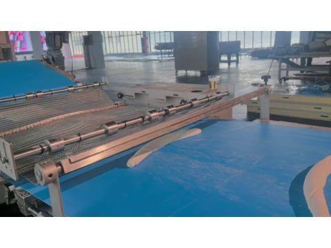 An automatic baguette moulding system showing shaped dough pieces emerging from the stainless steel rolling mesh elongator.