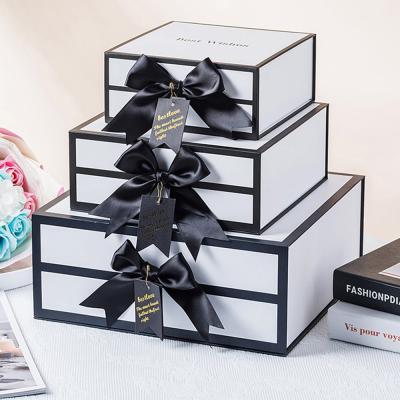 中国 Rigid White Magnetic Cardboard Gift Boxes With Black Rim And Ribbon Bow 販売のため