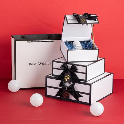 中国 Rigid White Magnetic Cardboard Gift Boxes With Black Rim And Ribbon Bow 販売のため