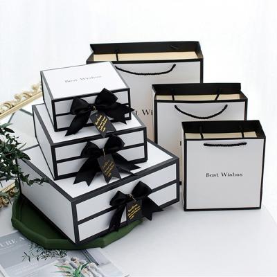 中国 Rigid White Magnetic Cardboard Gift Boxes With Black Rim And Ribbon Bow 販売のため