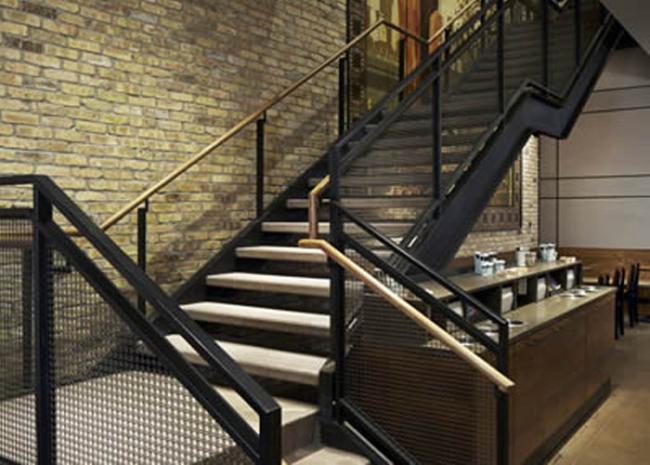 Woven wire cloth infill panels are used as stair railings in the store.