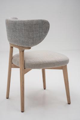 China Luxury Dining Chair With Sculptural Solid Wood Frame And Textured Fabric Upholstery For Modern Dining Spaces for sale