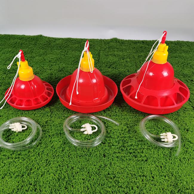 Red poultry drinker showing cylindrical design and water trough