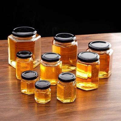Cina Vaso esagonale in vetro a colori personalizzati per miele di crema 45ml 180ml 500ml 700ml in vendita