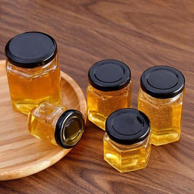 Cina Vaso esagonale in vetro a colori personalizzati per miele di crema 45ml 180ml 500ml 700ml in vendita