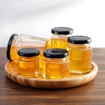 Cina Vaso esagonale in vetro a colori personalizzati per miele di crema 45ml 180ml 500ml 700ml in vendita