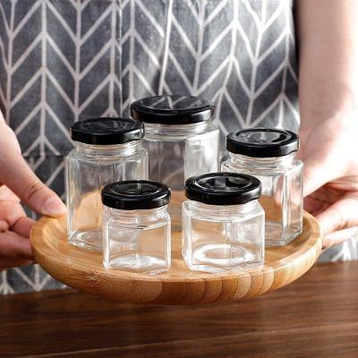 Cina Vaso esagonale in vetro a colori personalizzati per miele di crema 45ml 180ml 500ml 700ml in vendita