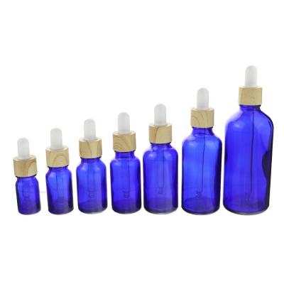 China High Quality Color Glass Blue Eye Droppers Empty Essential Oil Refillable Bottle With White Rubber Cap Wooden Circle for sale