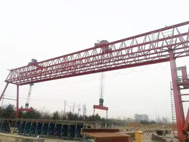 Industrial gantry rail crane lifting heavy containers at harbor terminal