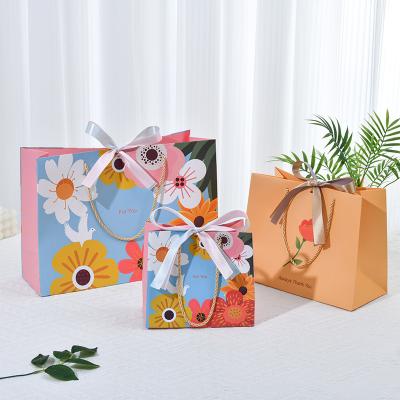 China ​​Premium Floral Gift Bag With Gold Twine Handles Chic Bow Vibrant Blue Multicolor Bloom Design for sale