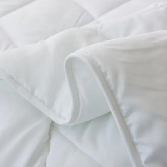 Close-up of diamond quilting pattern on white comforter