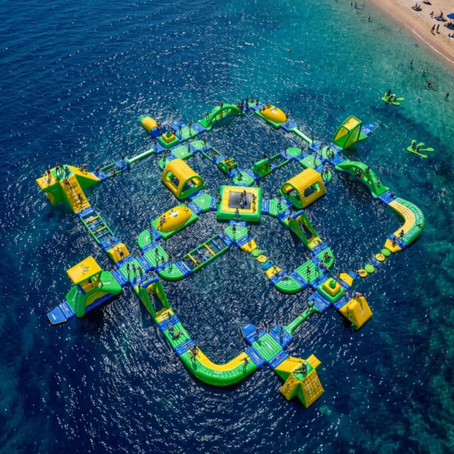 Large inflatable water park structure with multiple slides and climbing elements